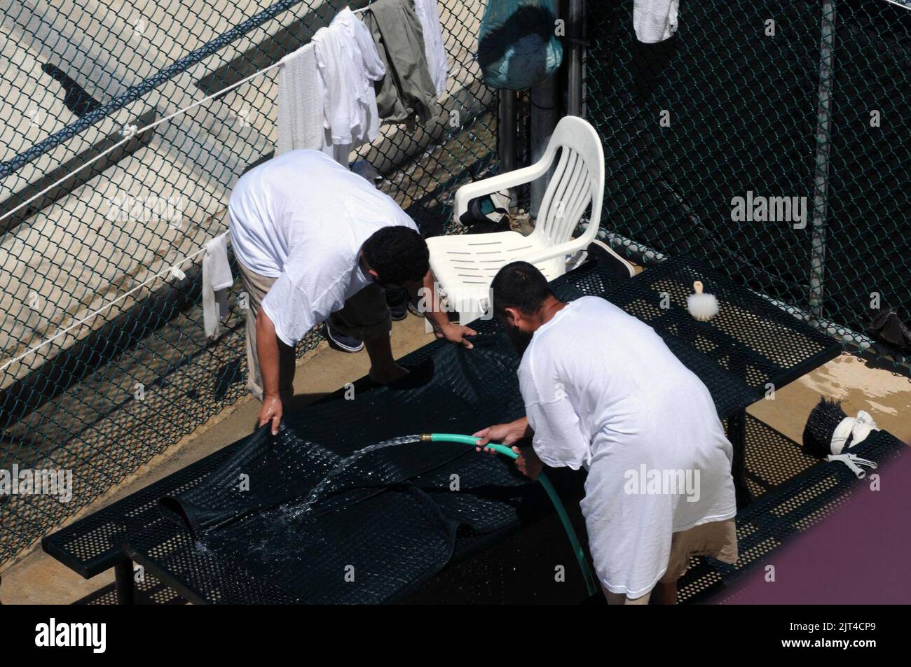 Two detainees wash a mat in the outdoor recreation area of Camp Six at ...