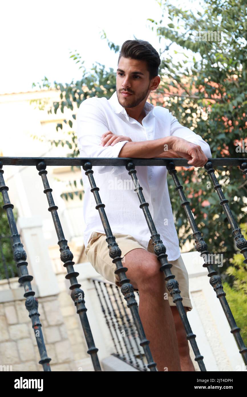 Stylish Spanish man in summer outfit is posing in the yard, next to ...