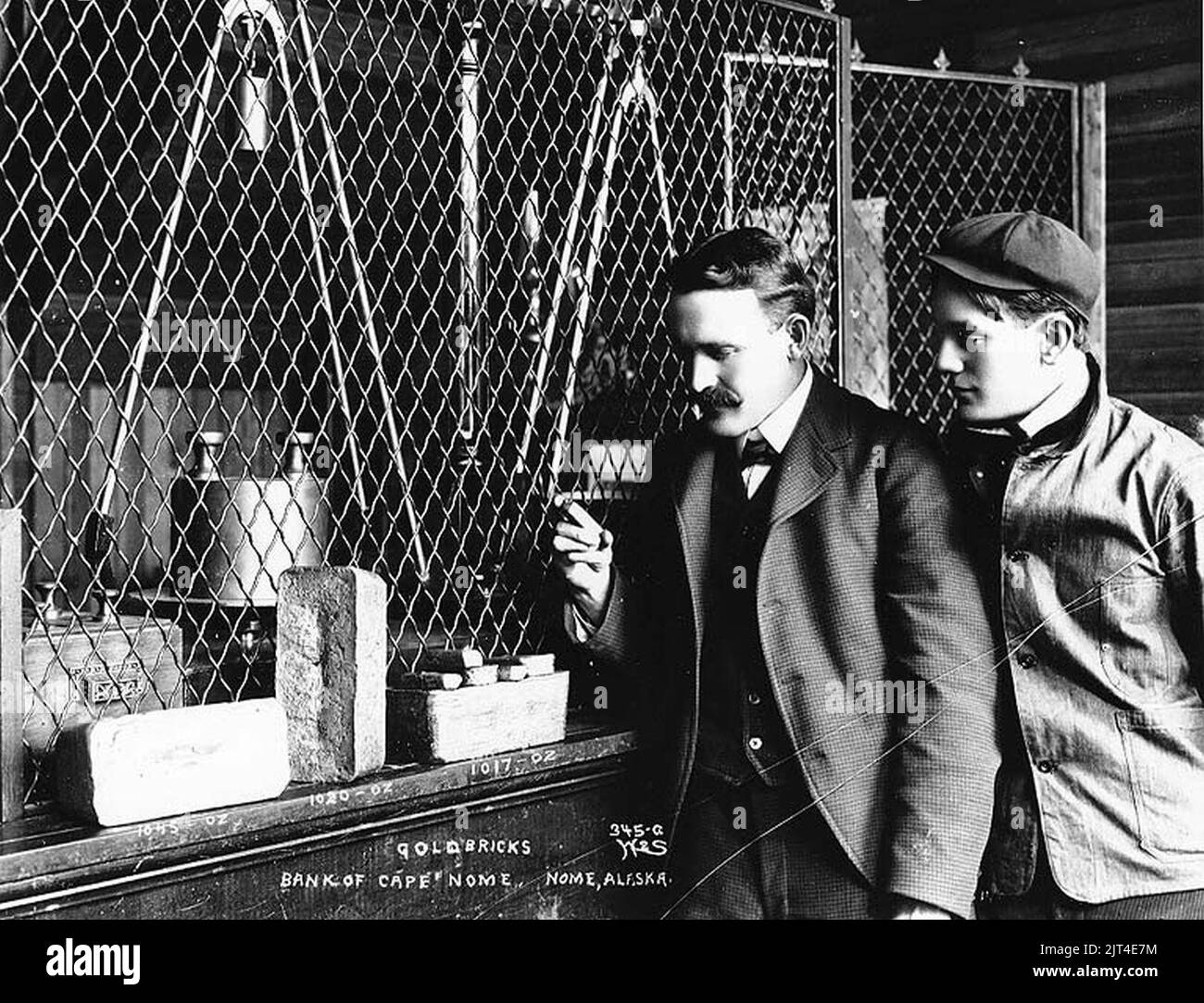 Two men standing with goldbricks inside the Bank of Cape Nome, Nome ...