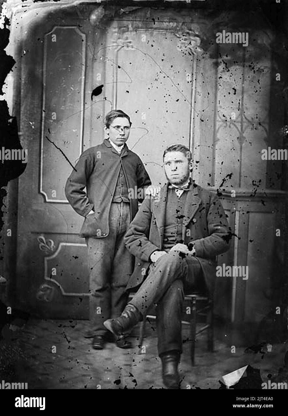 Two men, one standing and the other sitting Stock Photo - Alamy