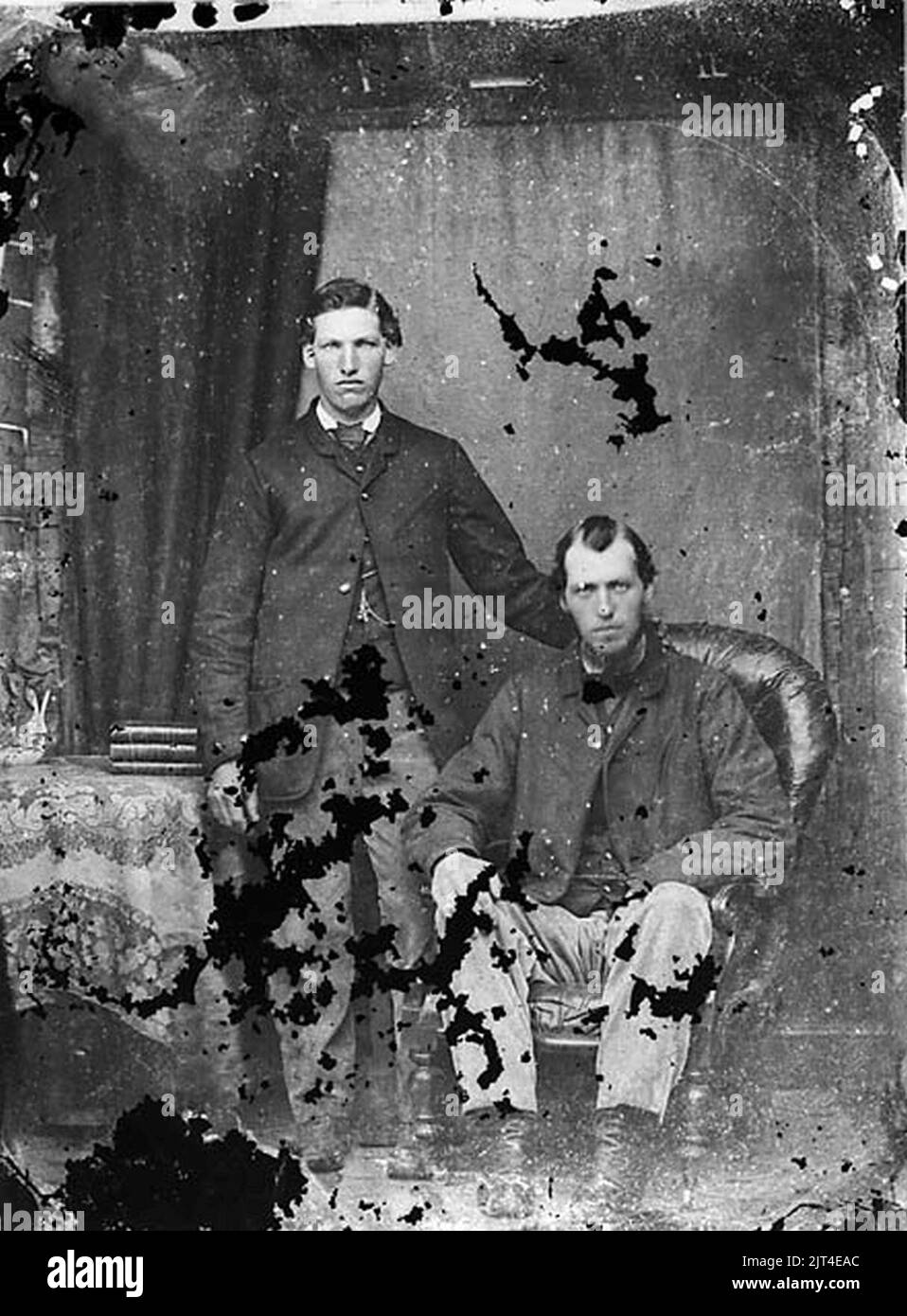 Two men, one standing and the other sitting Stock Photo - Alamy