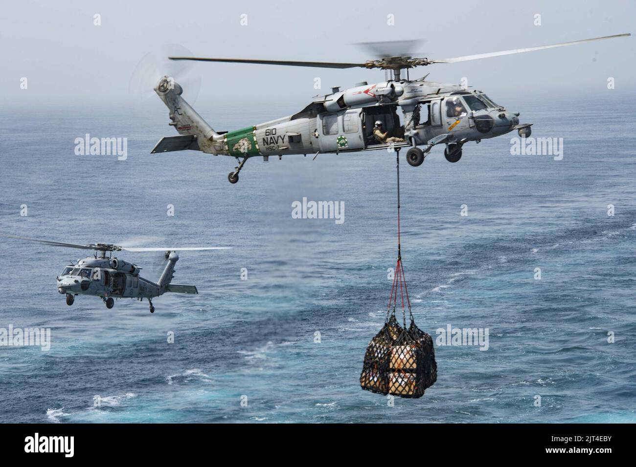 Two MH-60S Sea Hawk helicopters transport cargo to the flight deck of ...