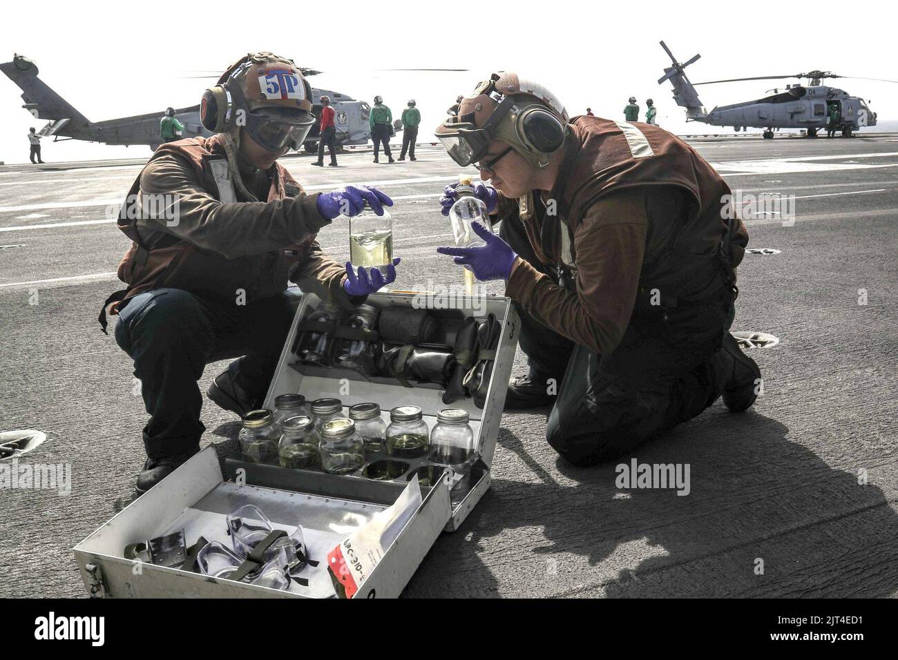 Two Navy Airmen test fuel samples on the flight deck of USS Abraham ...