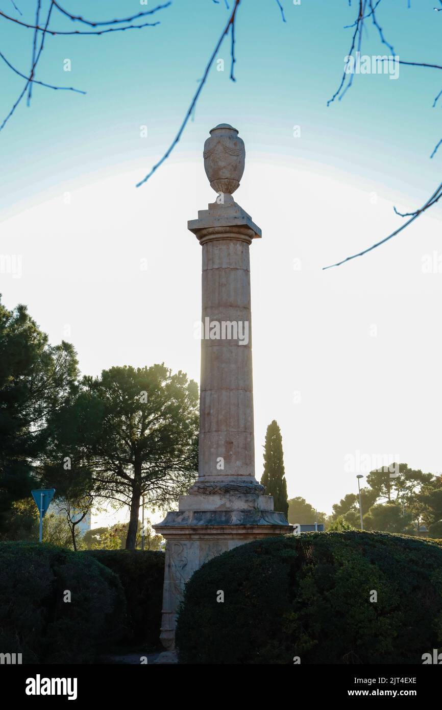 A vertical shot of a marble column monument in the park with trees ...