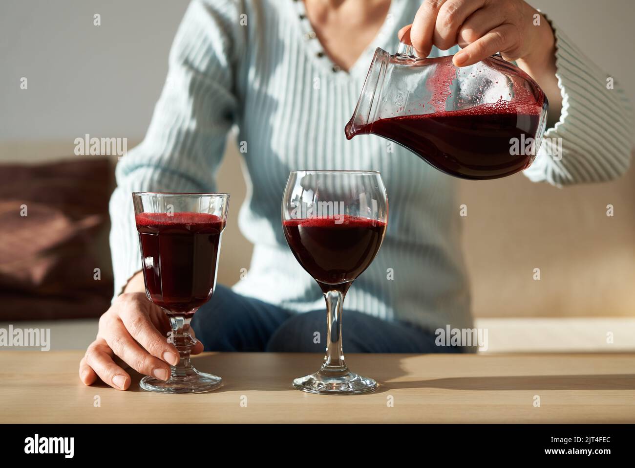 Pouring fresh homemade red beet juice from a jug into two glasses ...
