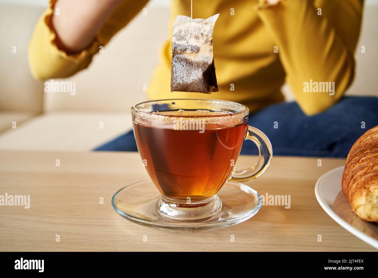 A tea bag is being lifted above the cup by a teenage girl, with a ...