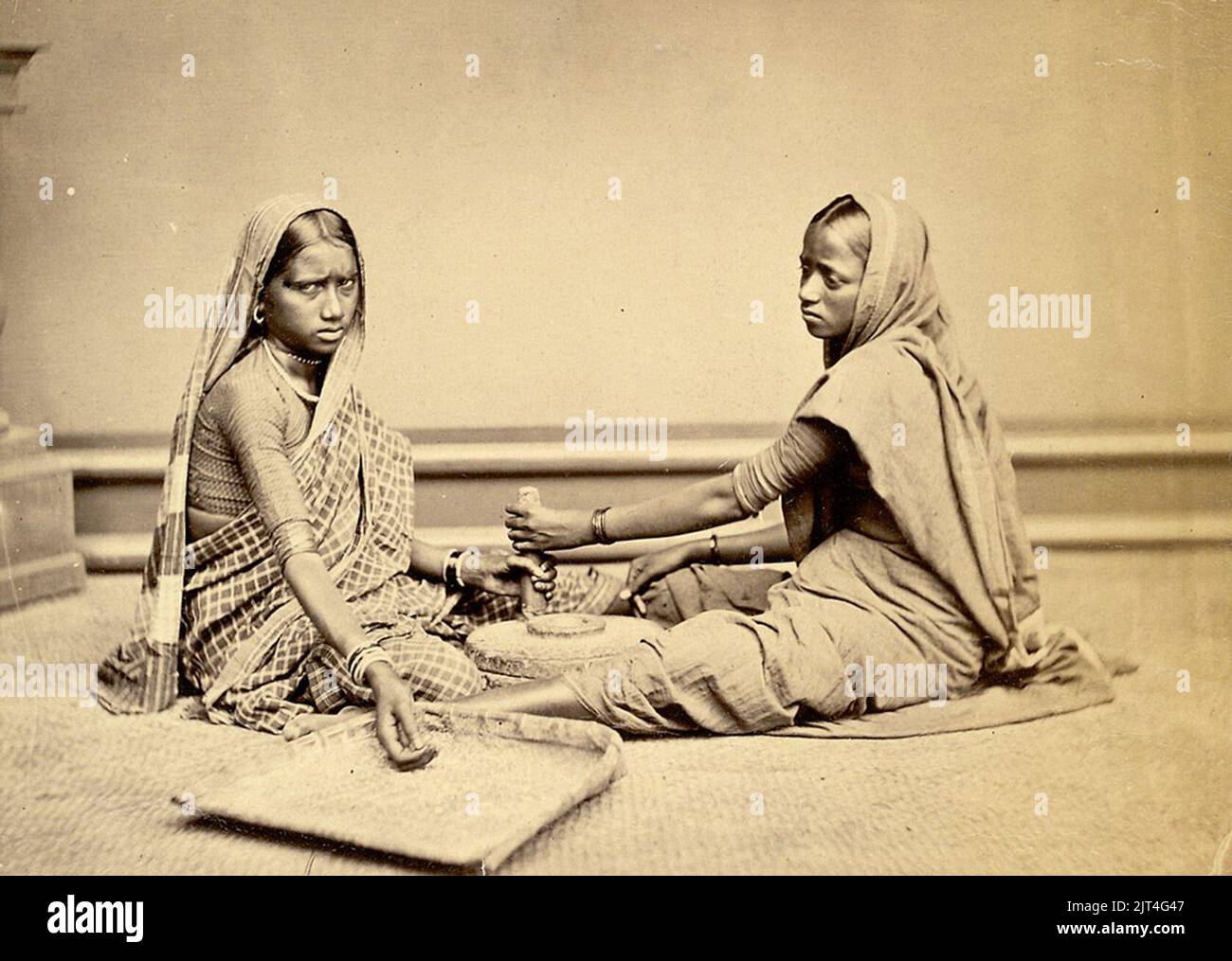 Two women grinding food grain at a mill - 1873 Stock Photo - Alamy