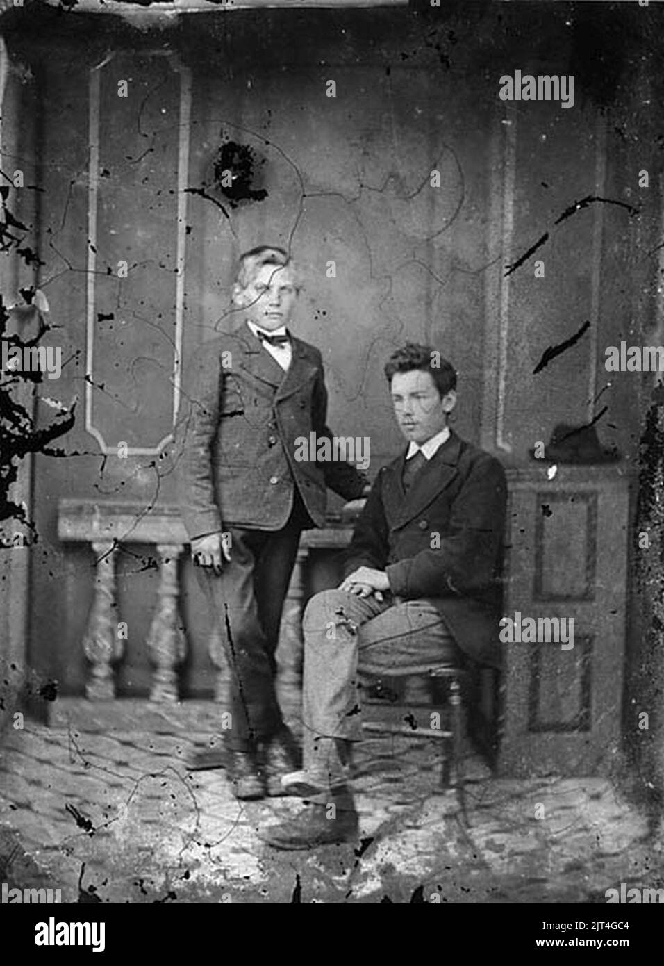 Two young men, one standing and the other sitting Stock Photo - Alamy