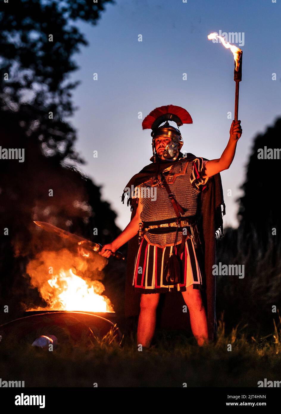 Roman living history reenactor holds a flaming torch next to a fire ...