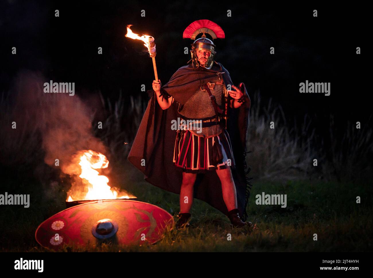 Roman living history reenactor holds a flaming torch next to a fire ...