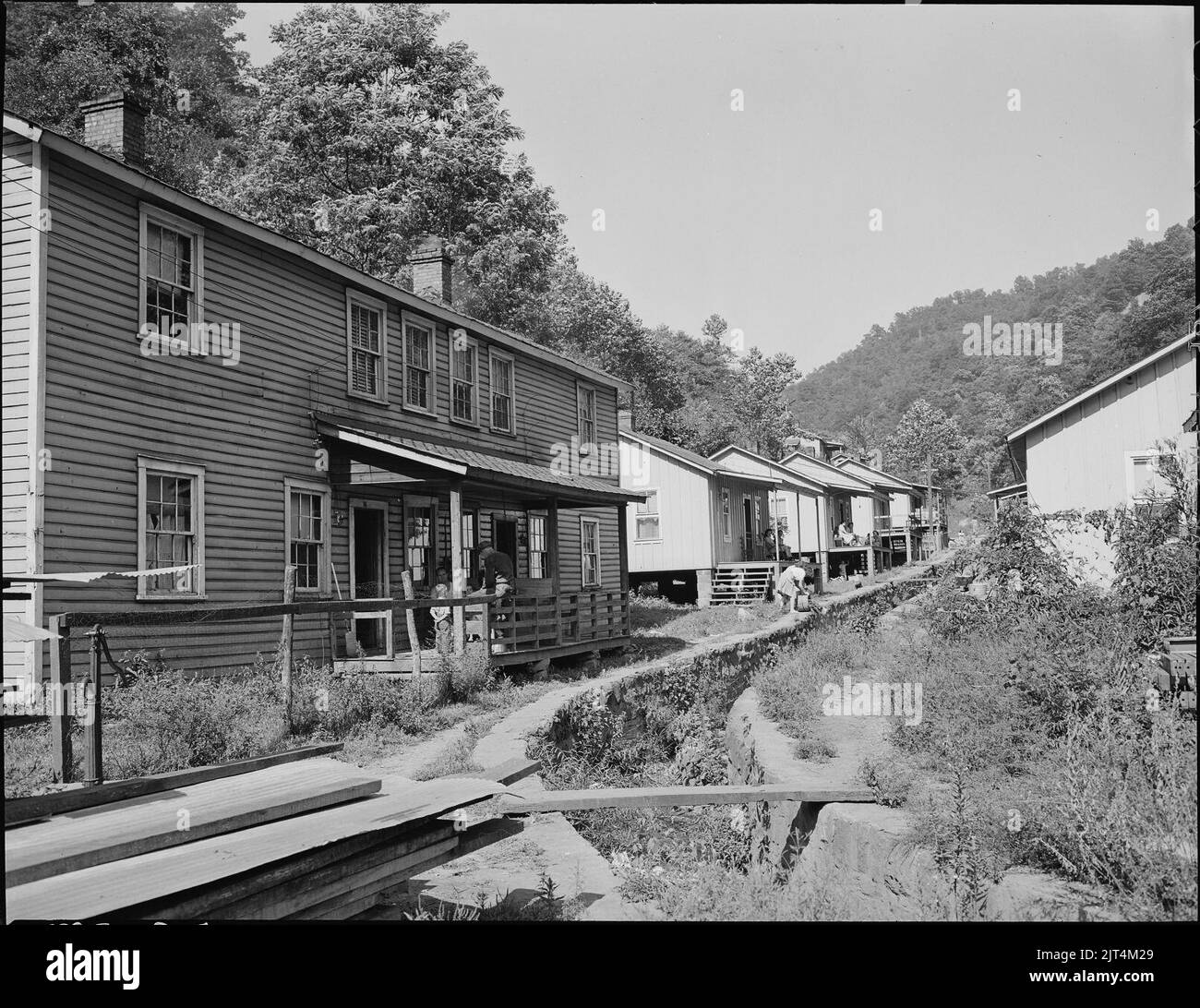 Typical housing, notice the small girl throwing garbage into stream ...