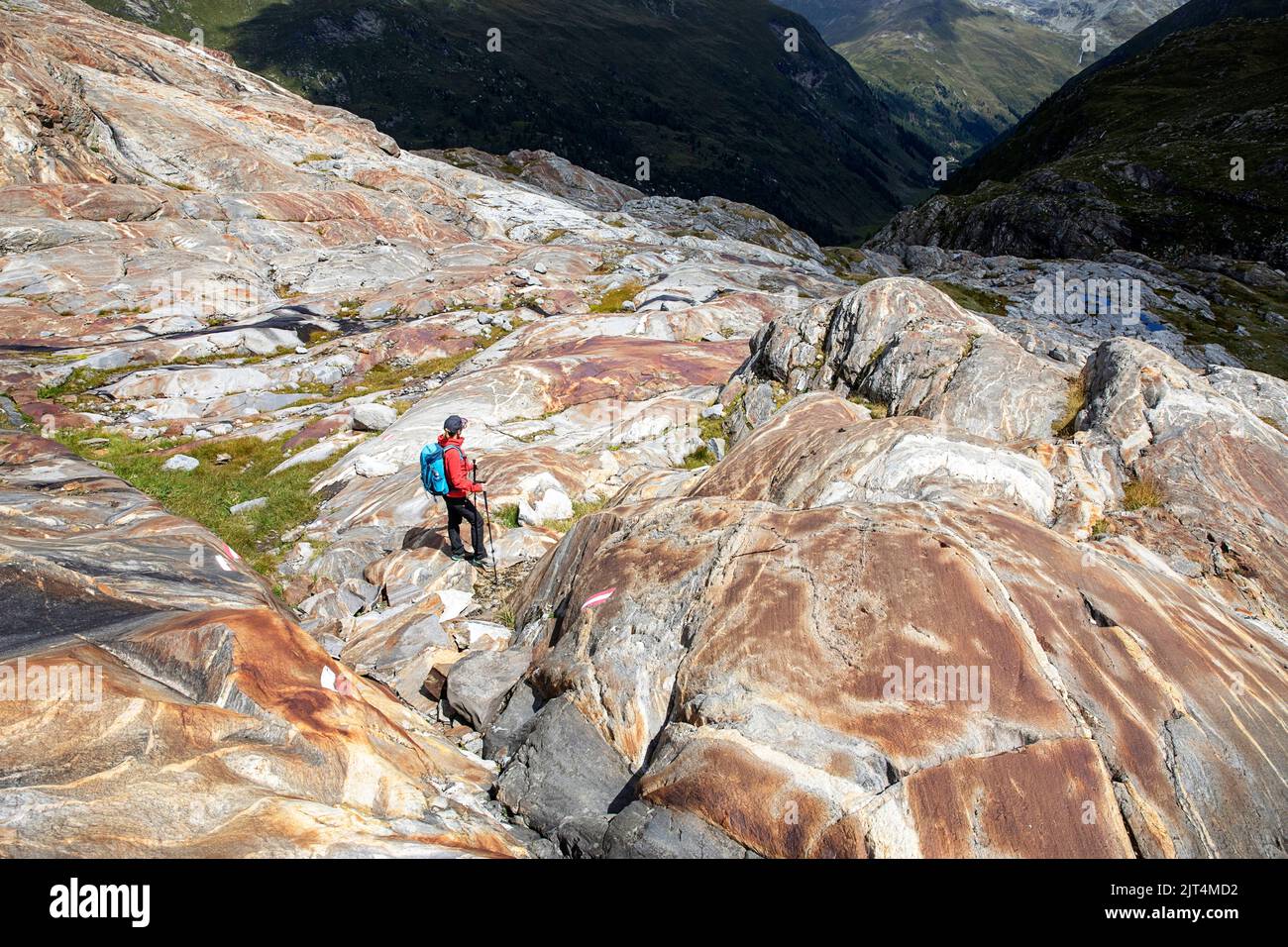 Woman hiking over colorful rocks on a glacier moraine on a beautiful ...