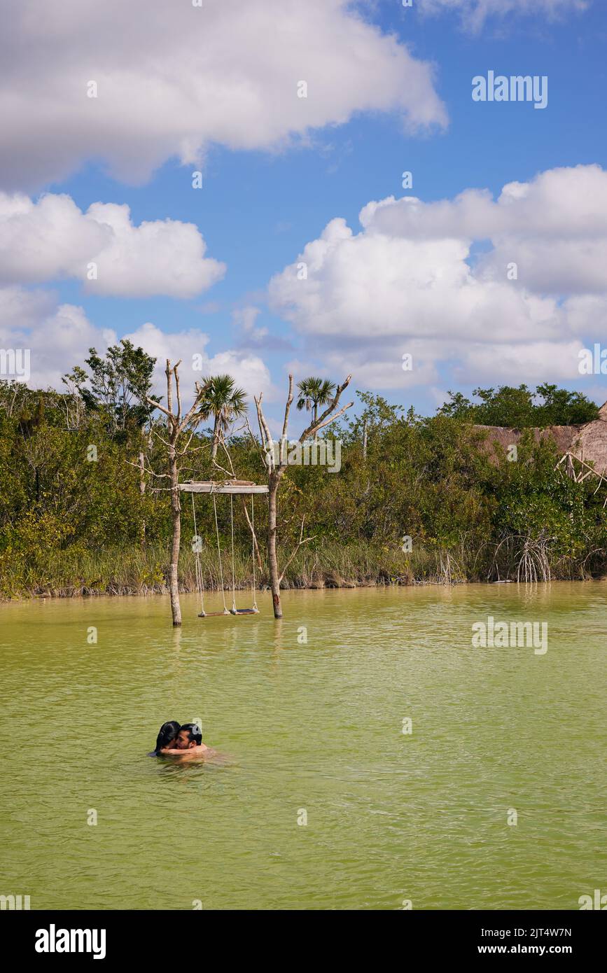A vertical shot of an embracing couple in the Cenote Lagoon Kaan Luum ...