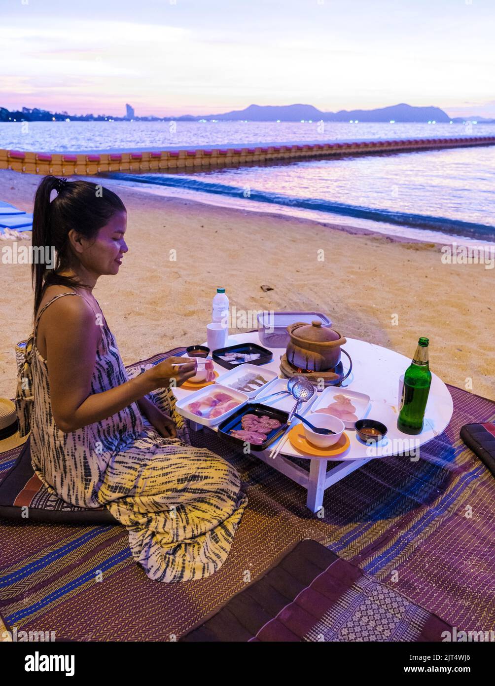women bbq cooking noodle soup during sunset in Thailand Ban Amphur beach. relaxing with bbq Thai ...