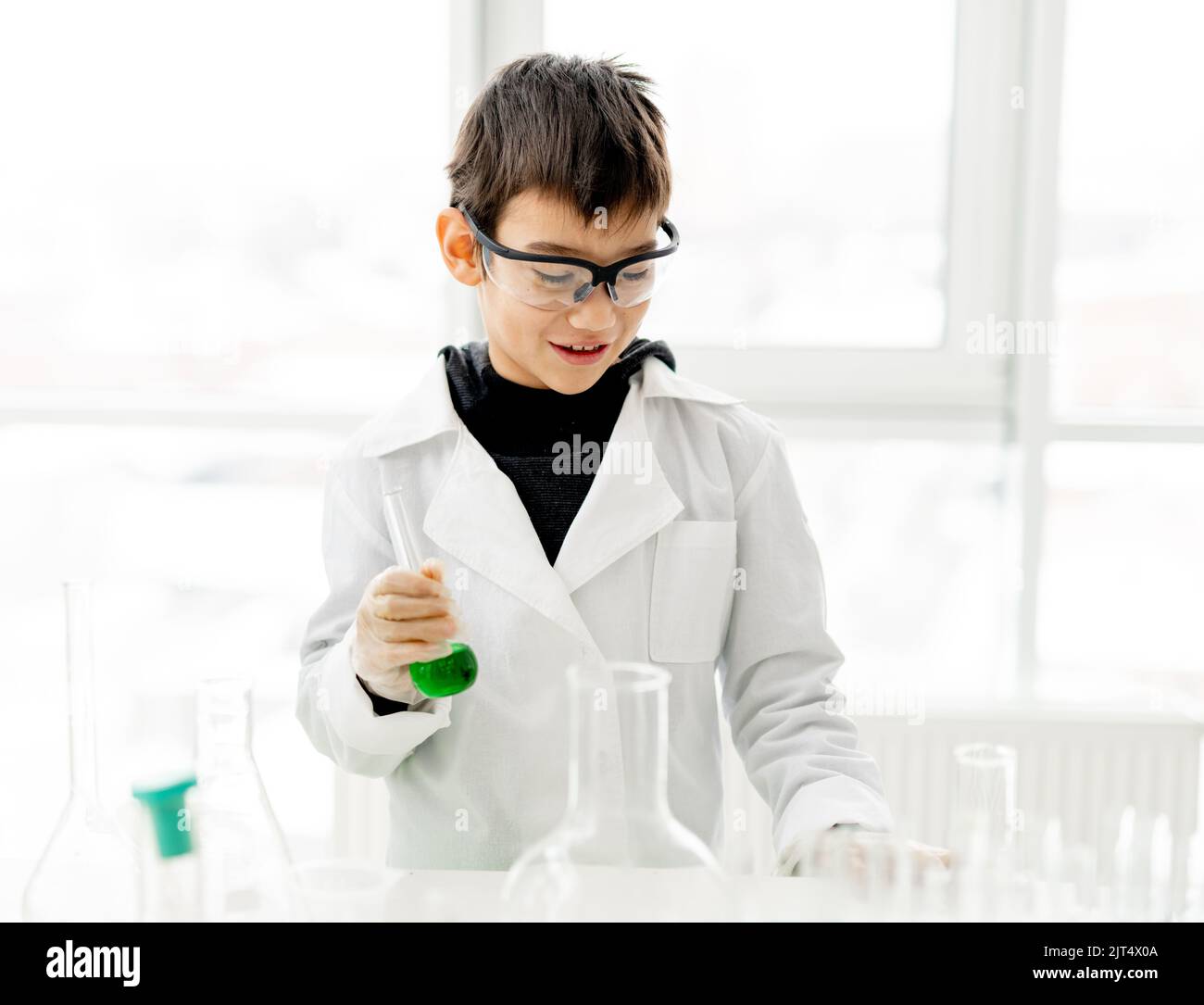 School boy wearing protection glasses doing chemistry experiment in ...