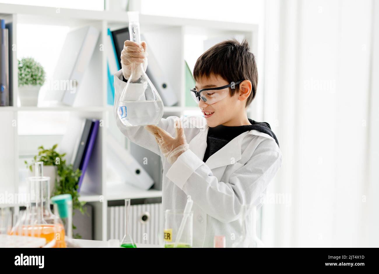 School boy wearing protection glasses doing chemistry experiment ...
