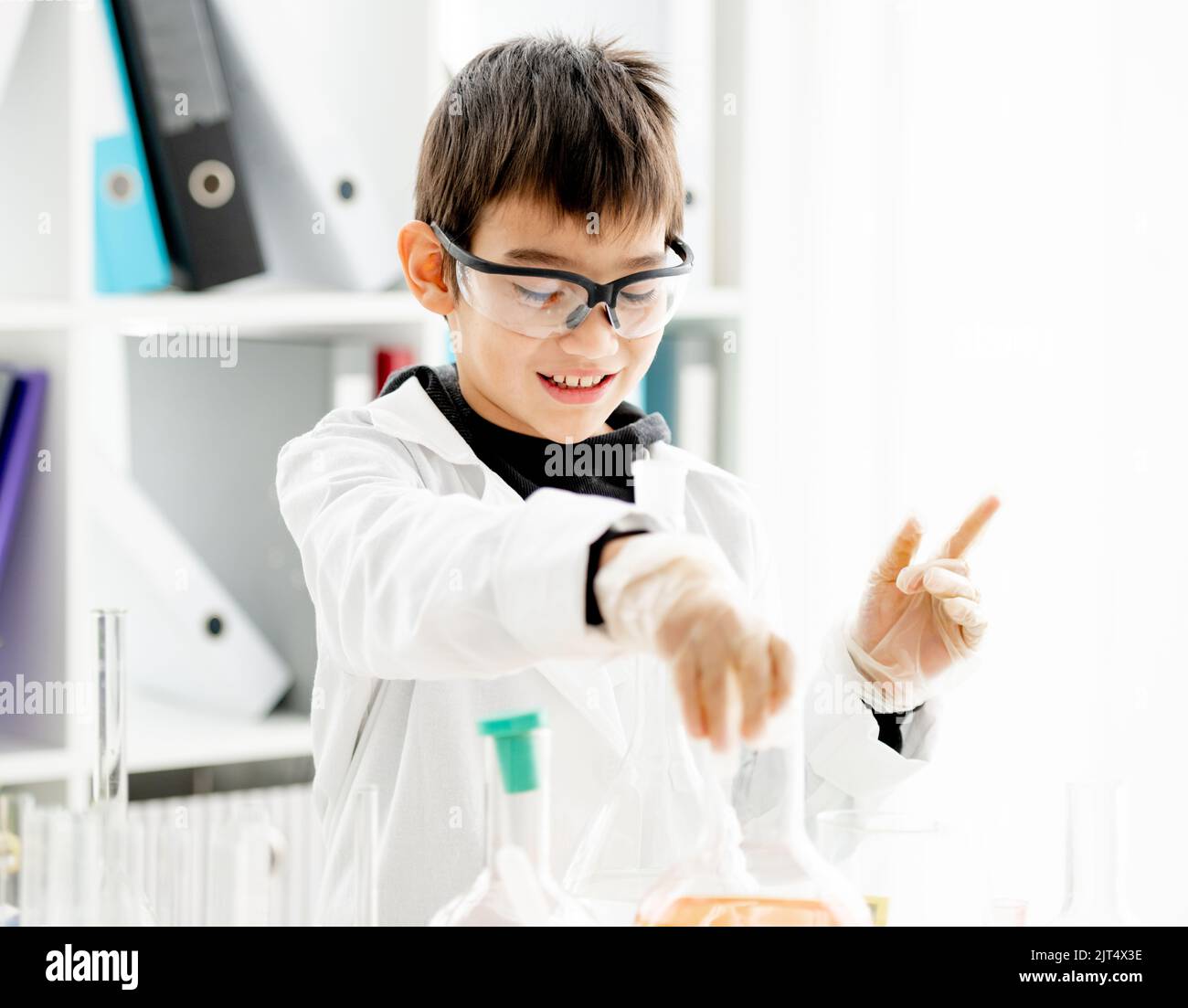School boy wearing protection glasses doing chemistry experiment in ...