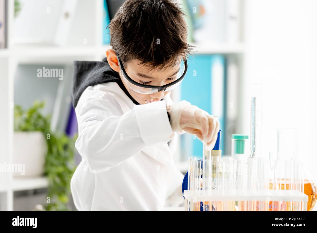 School boy wearing protection glasses doing chemistry experiment in ...