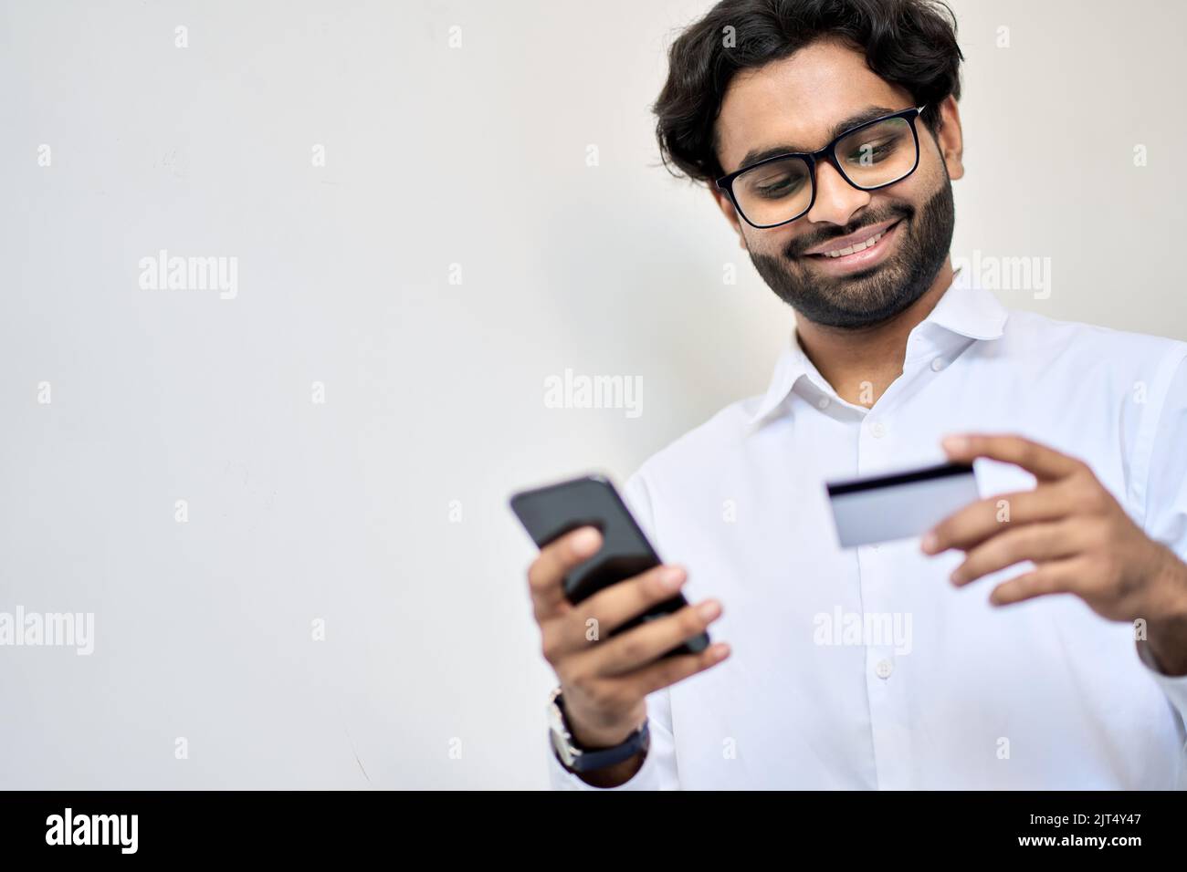 Smiling young indian business man using phone holding credit card Stock Photo - Alamy
