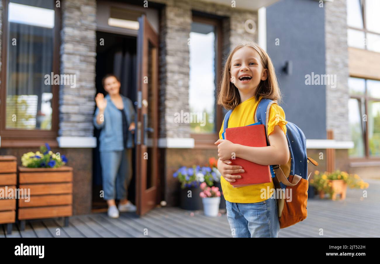 Parent and pupil of primary school going hand in hand. Woman and girl ...