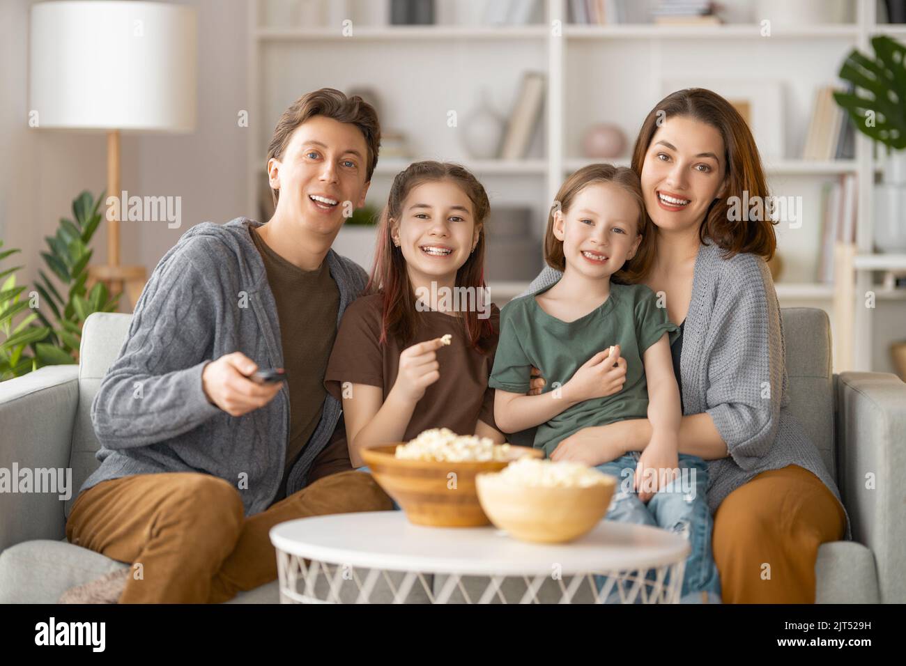 Happy family watching projector, TV, movies with popcorn in the evening ...