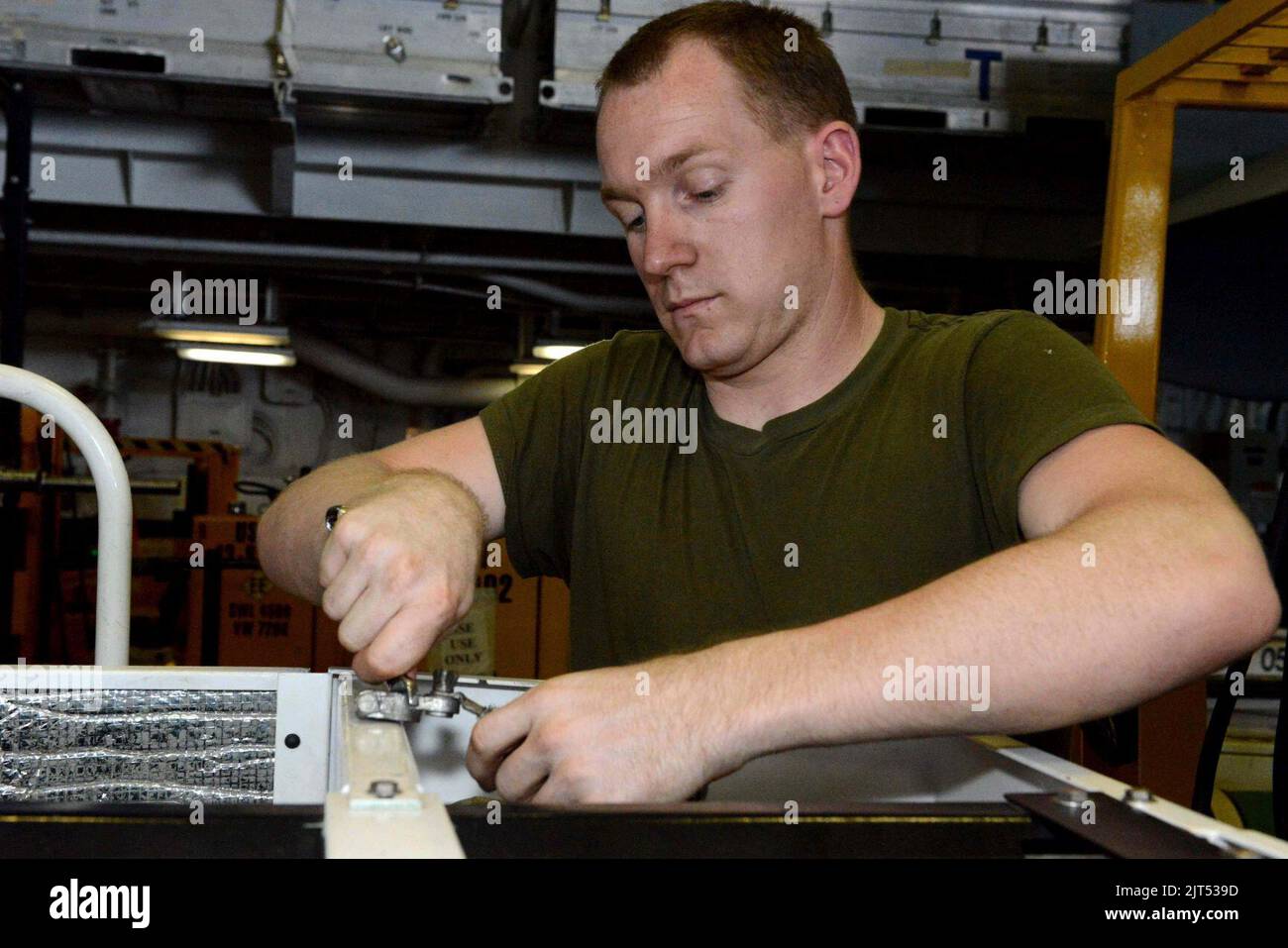 U.S. Marine Corps Cpl. tightens a battery terminal on a flight deck ...