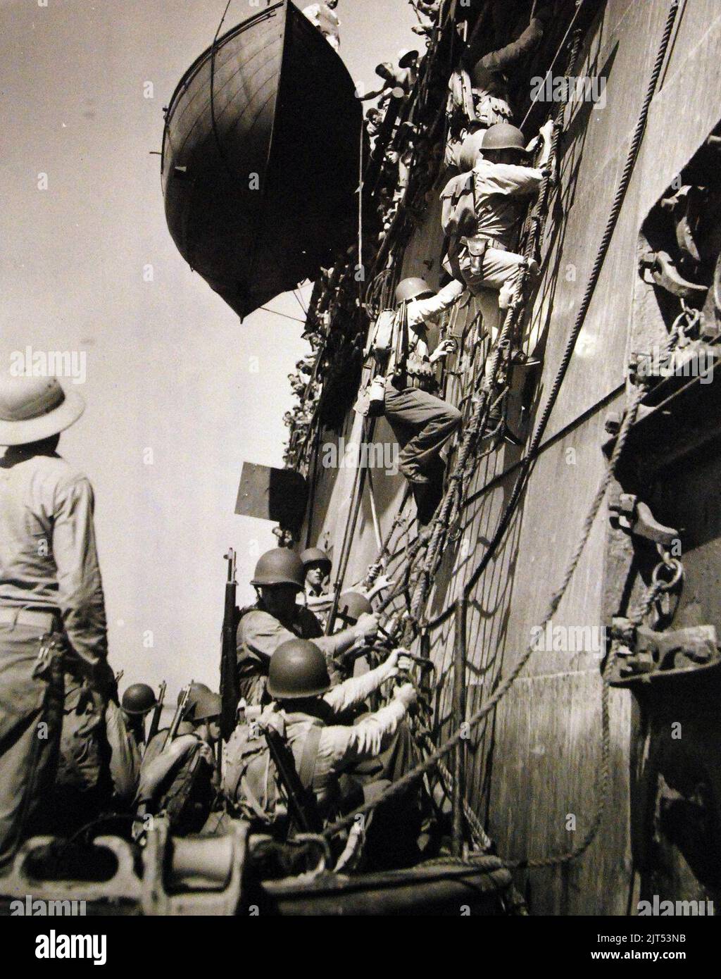 U.S. Marines climb down the rope nets of Army transport into landing ...