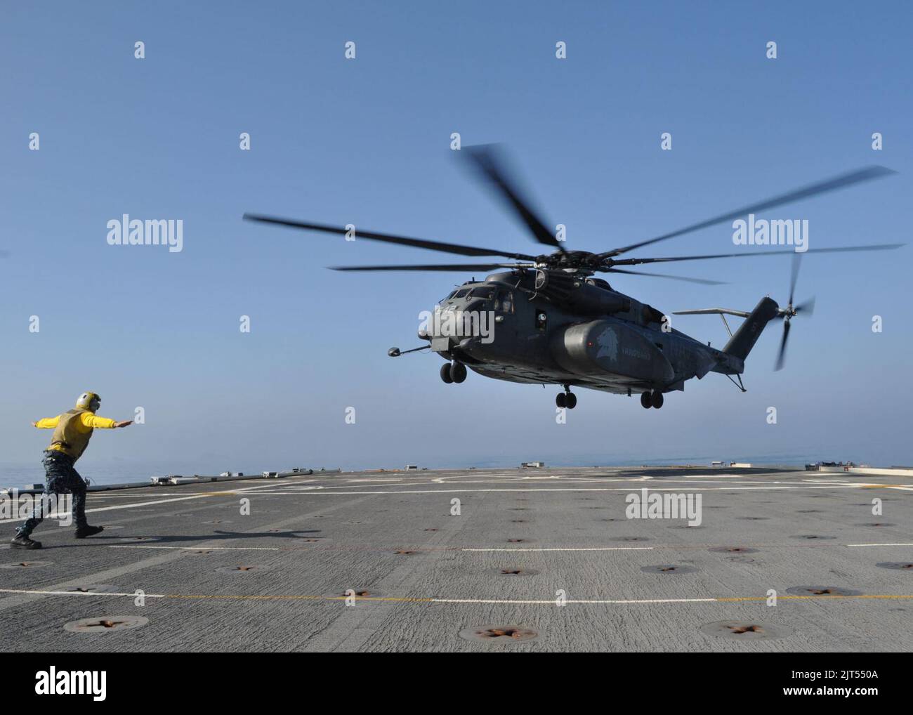 U.S. Navy Aviation Boatswain's Mate Fuel Airman signals an approaching MH-53E Sea Dragon ...