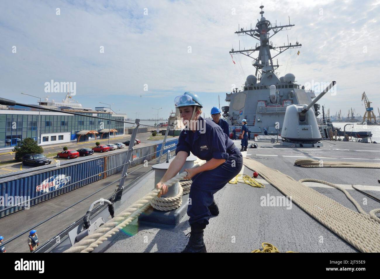 U.S. Navy Boatswain's Mate 3rd Class hauls in a mooring line aboard the ...