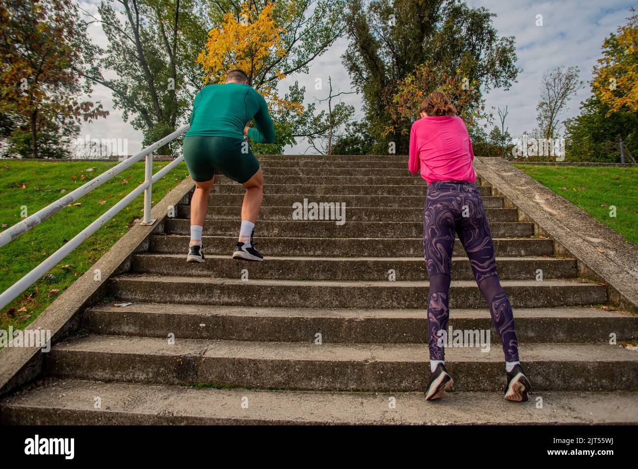 Two strong and fit friends are doing a jumping exercise on the stairs ...