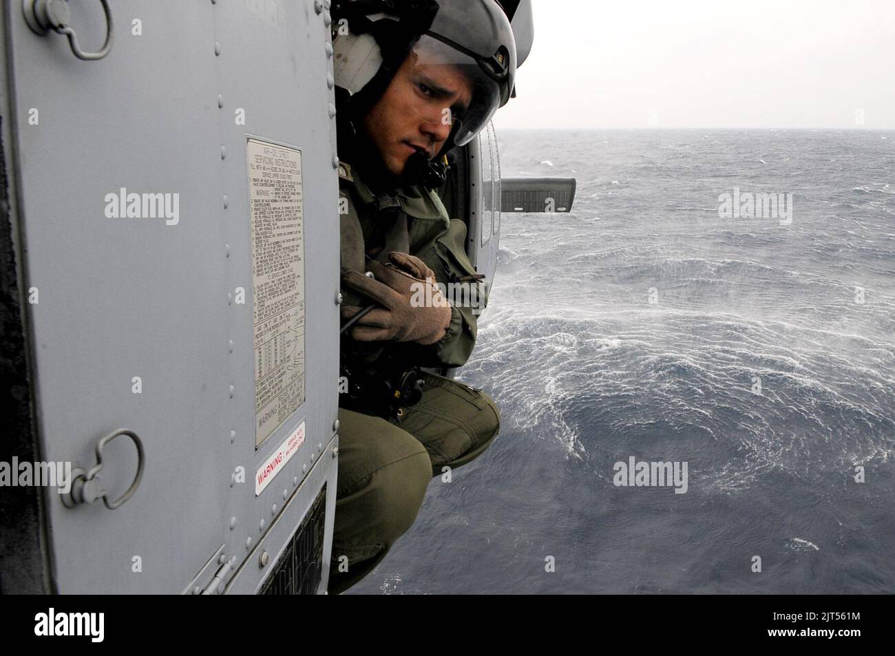 U.S. Navy Chief Naval Air Crewman monitors the distance to the water ...