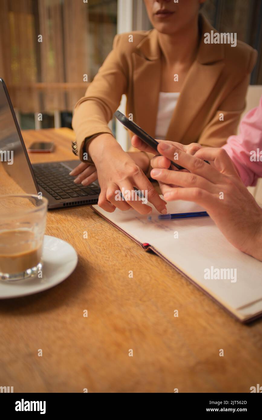 Young businesswoman is taking a pen to write a note down while working ...