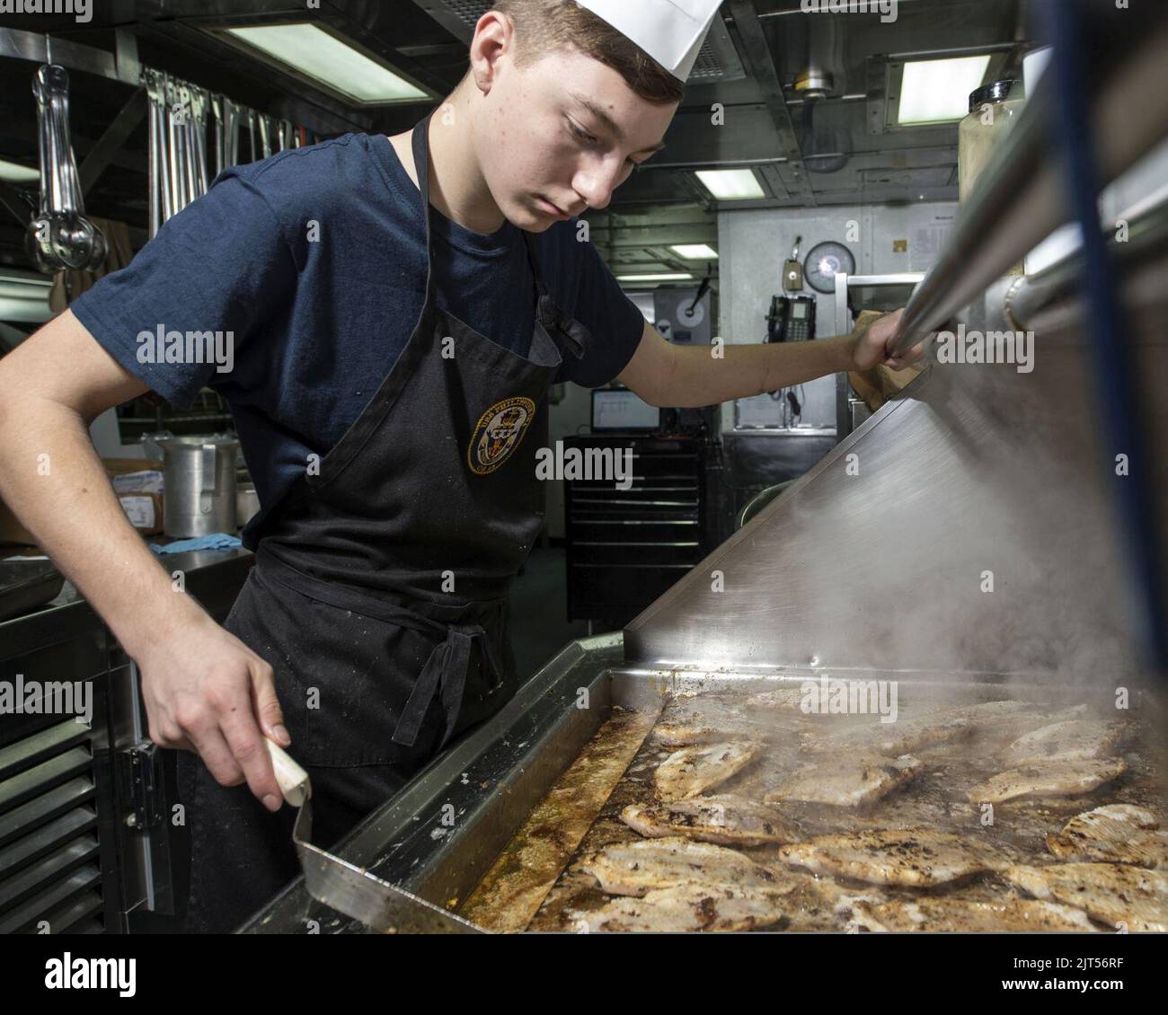 U.S. Navy Culinary Specialist Seaman grills fish aboard the guided ...