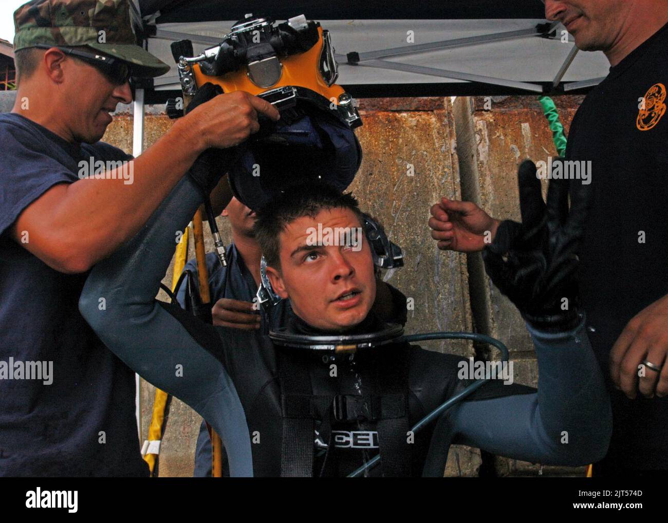 U.S. Navy Diver 2nd Class left, helps remove a diving helmet from Navy ...
