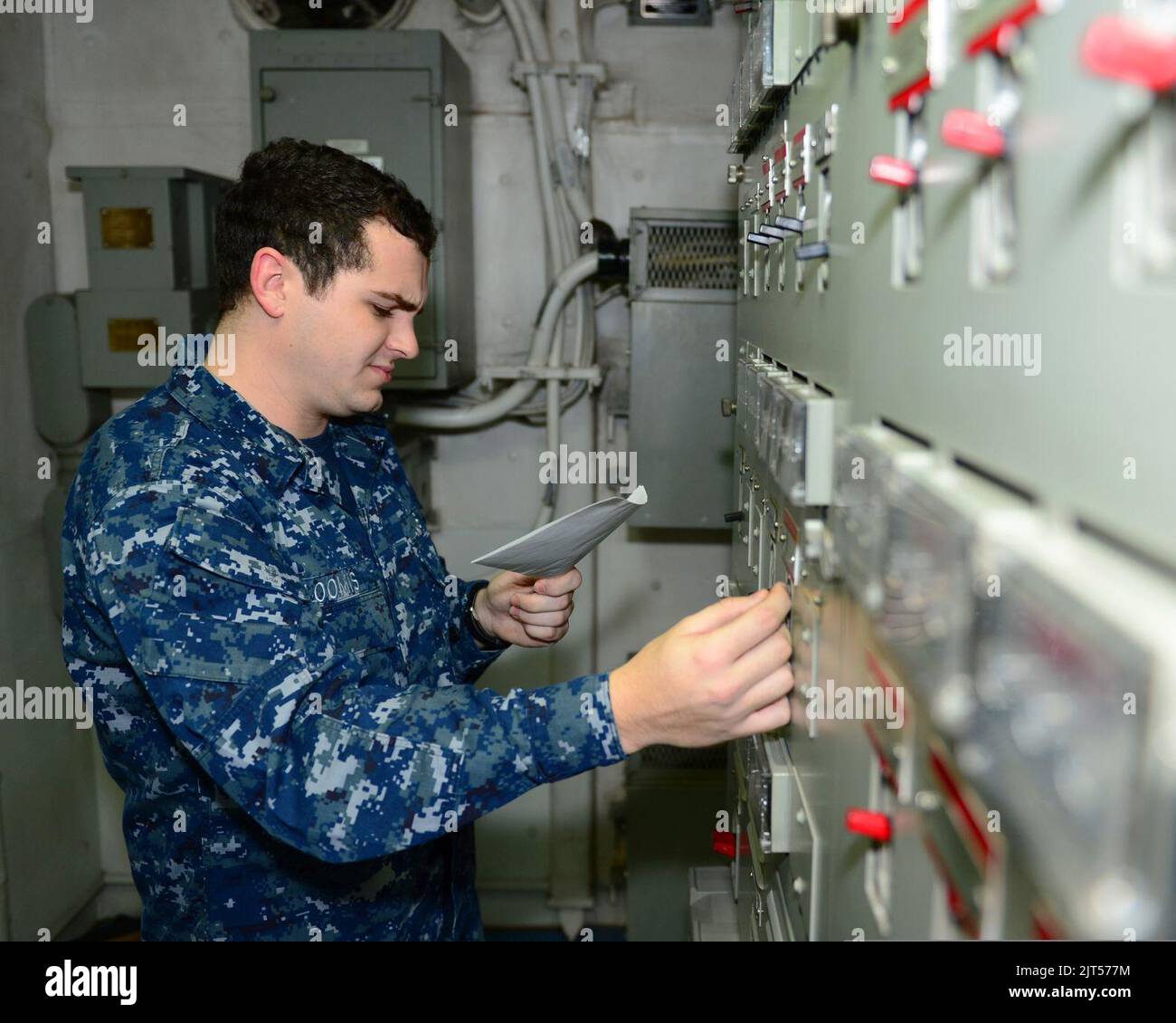 U.S. Navy Electrician's Mate Fireman secures power at a control panel ...