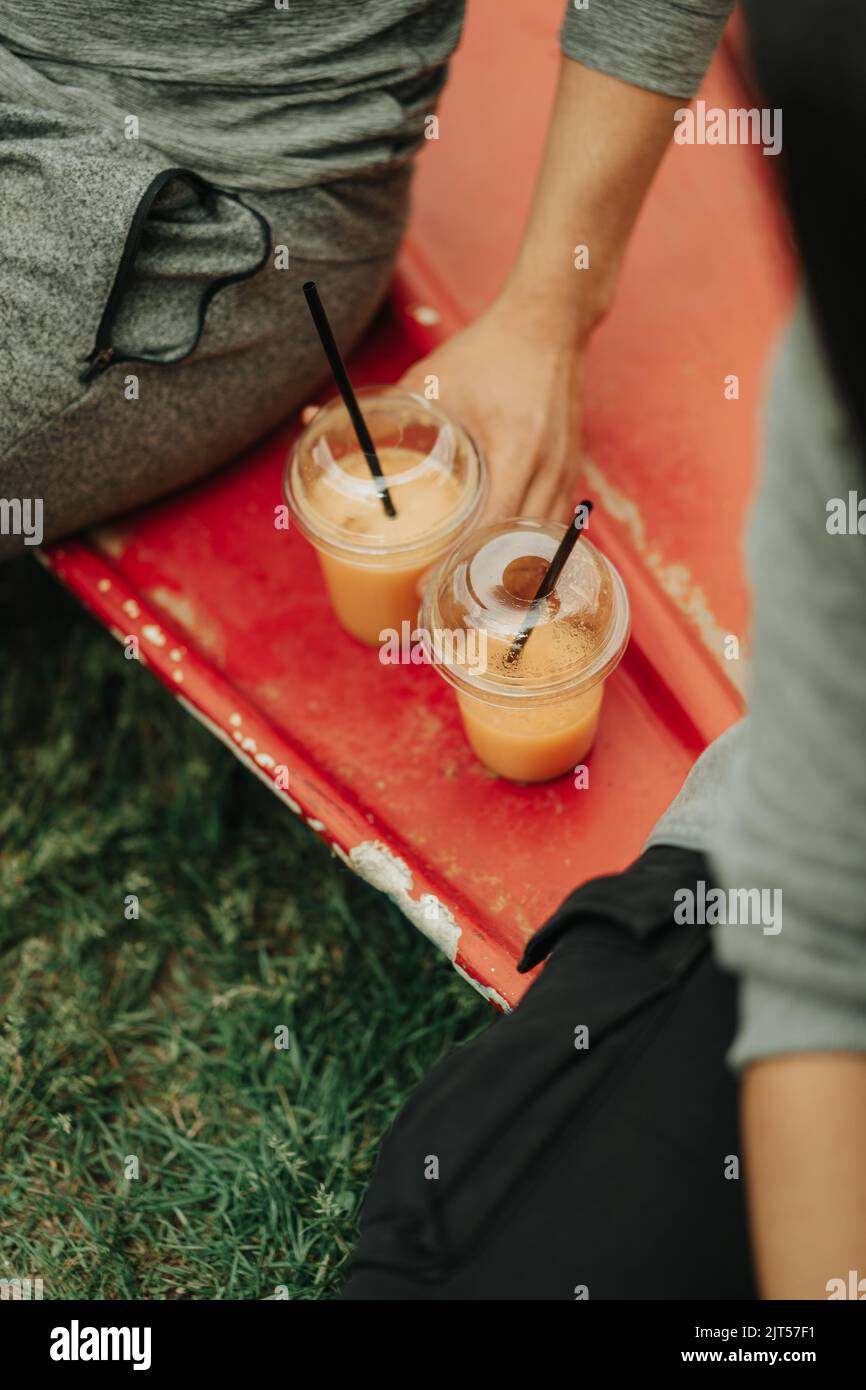Close up of cups of orange juice sitting on a red kayak in the park ...
