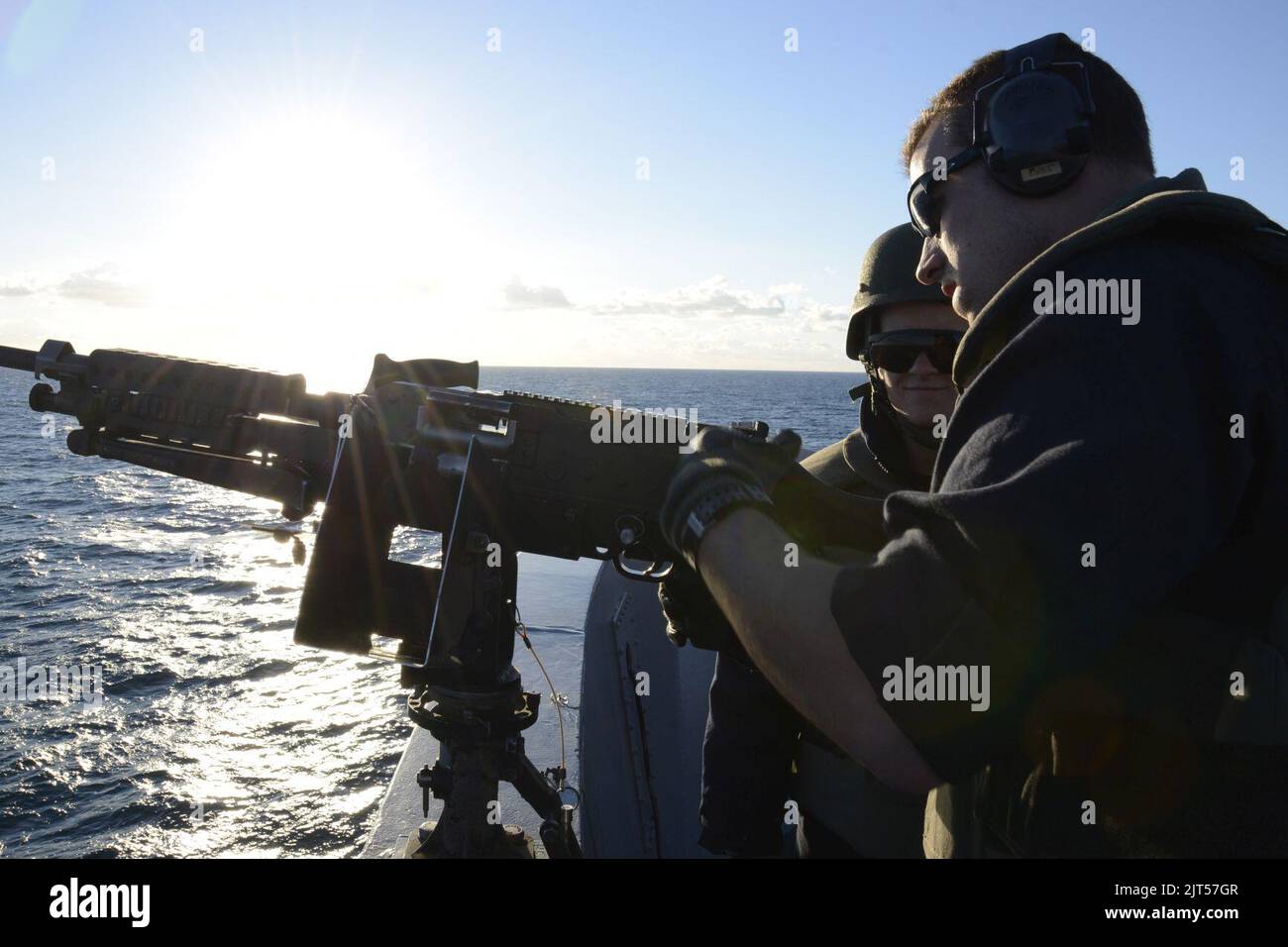 U.S. Navy Gunner's Mate foreground, demonstrates how to load a Mark 60 ...
