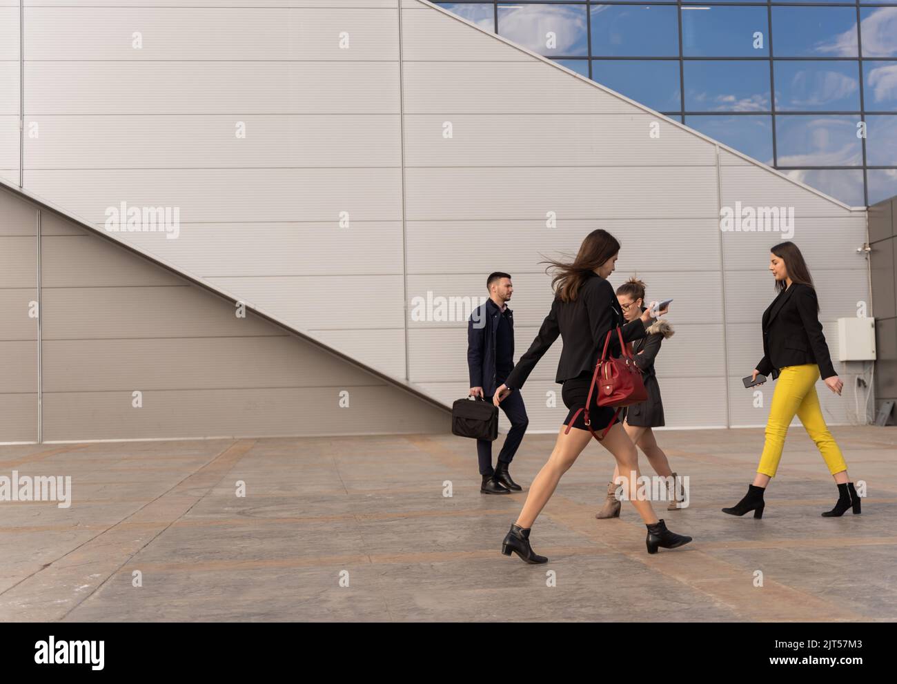 Group of young business people are walking fast towards their company ...