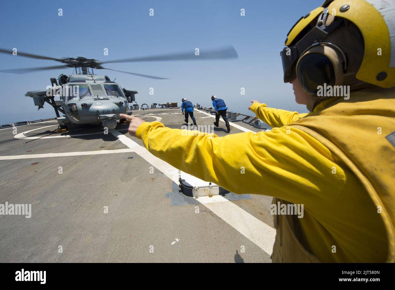 U.S. Navy Lt. j.g. signals Sailors to remove chocks and chains from an ...