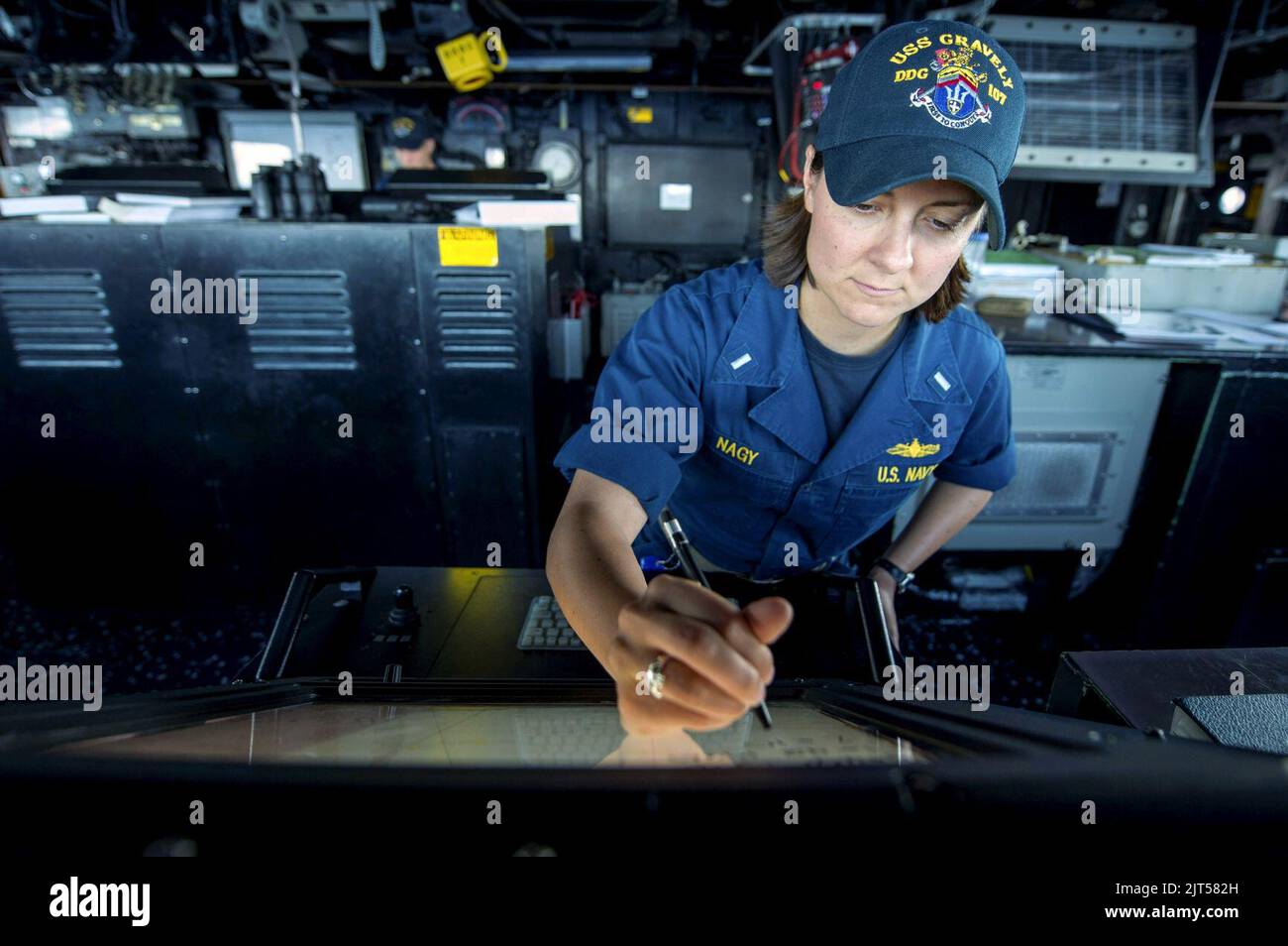 U.S. Navy Lt. j.g. tracks surface and air contacts on the bridge of the ...