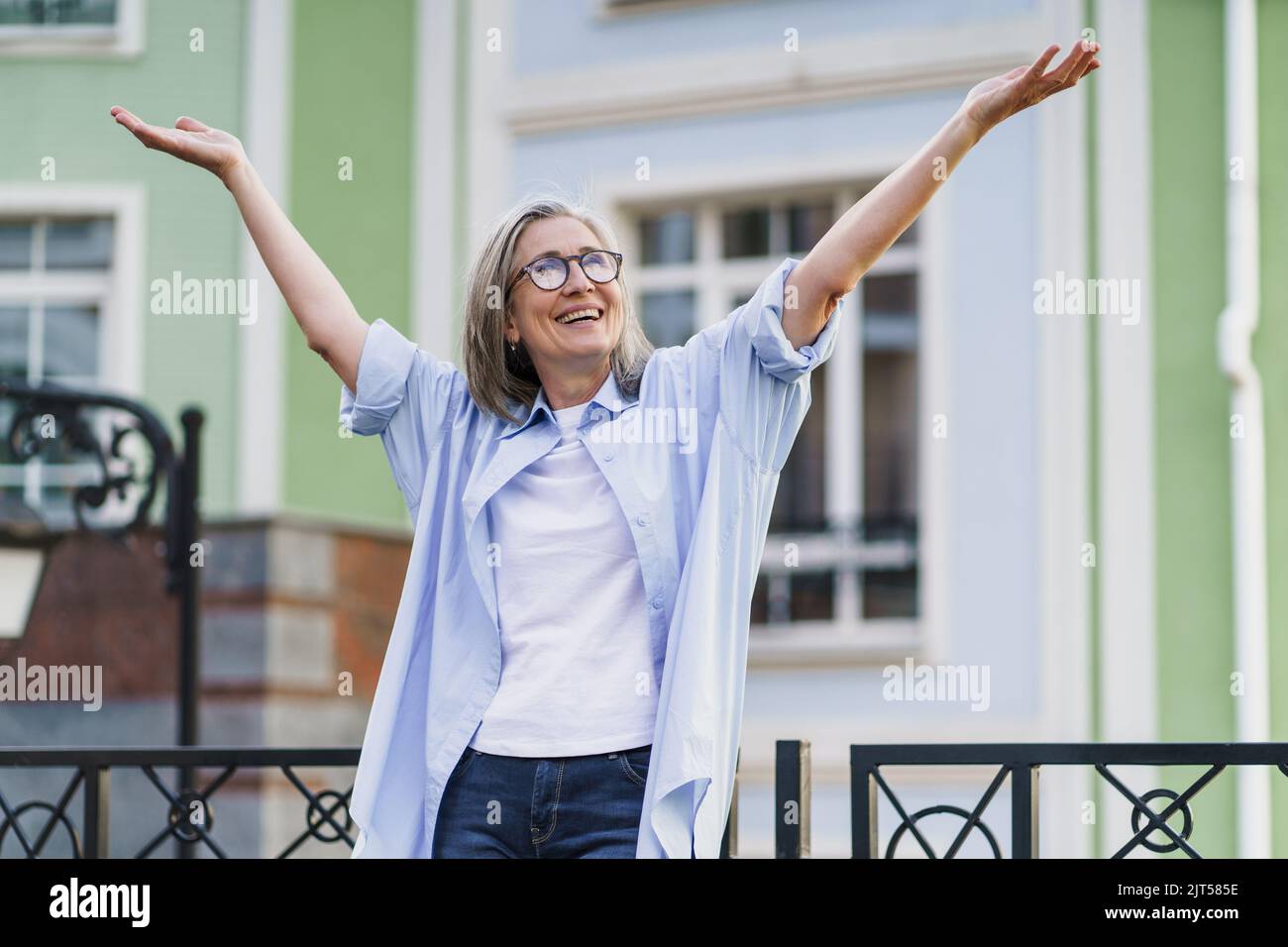 Happy excited mature woman with hands lifted up wearing glasses ...