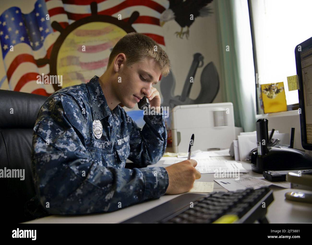 U.S. Navy Master-at-Arms Apprentice takes notes while on a phone call ...