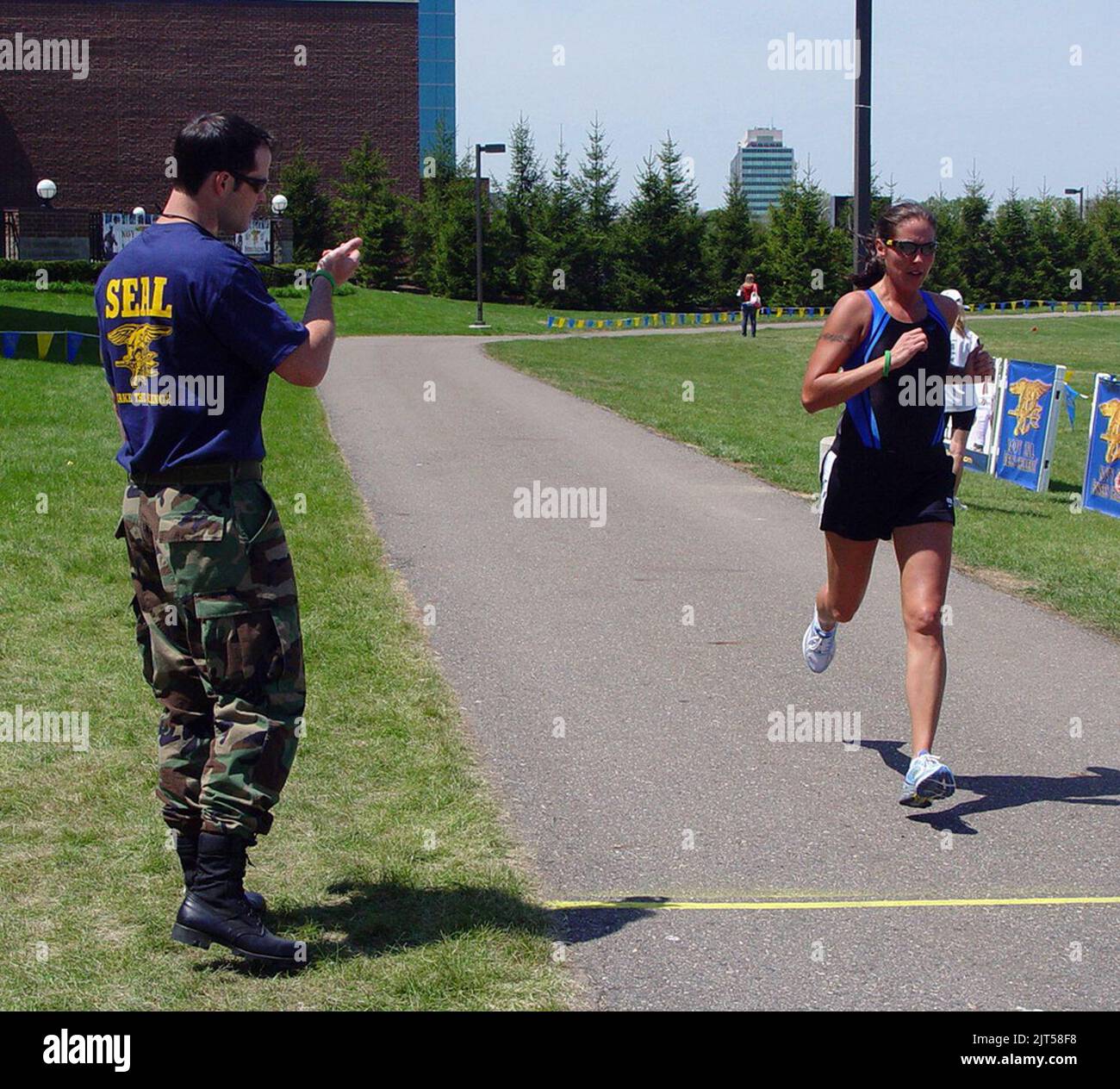 U.S. Navy Petty Officer 1st Class left, keeps time for a runner at the ...