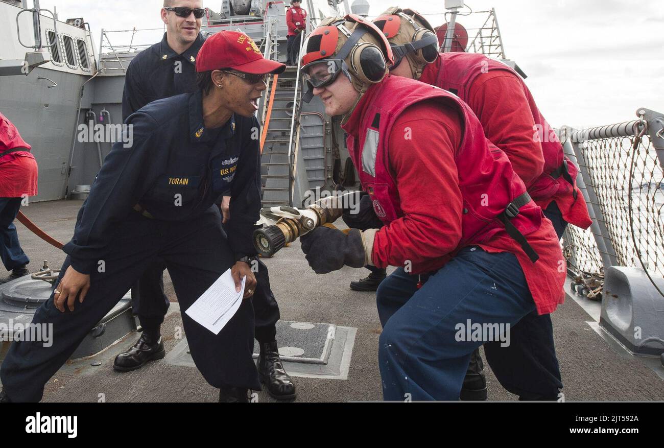U.S. Navy Senior Chief Damage Controlman front left, gives instructions ...