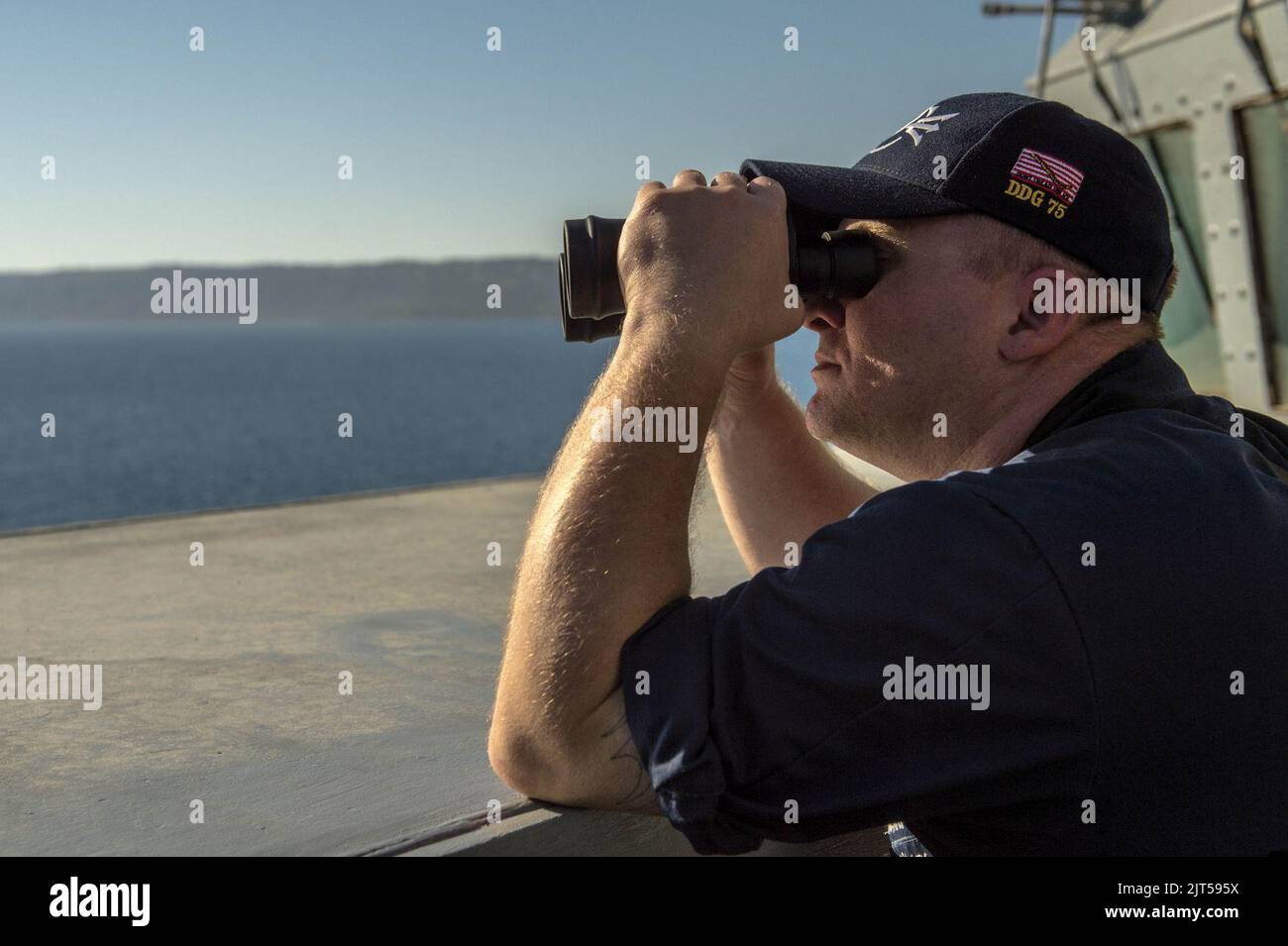 U.S. Navy Sonar Technician Surface 1st Class uses binoculars to track air and surface contacts ...