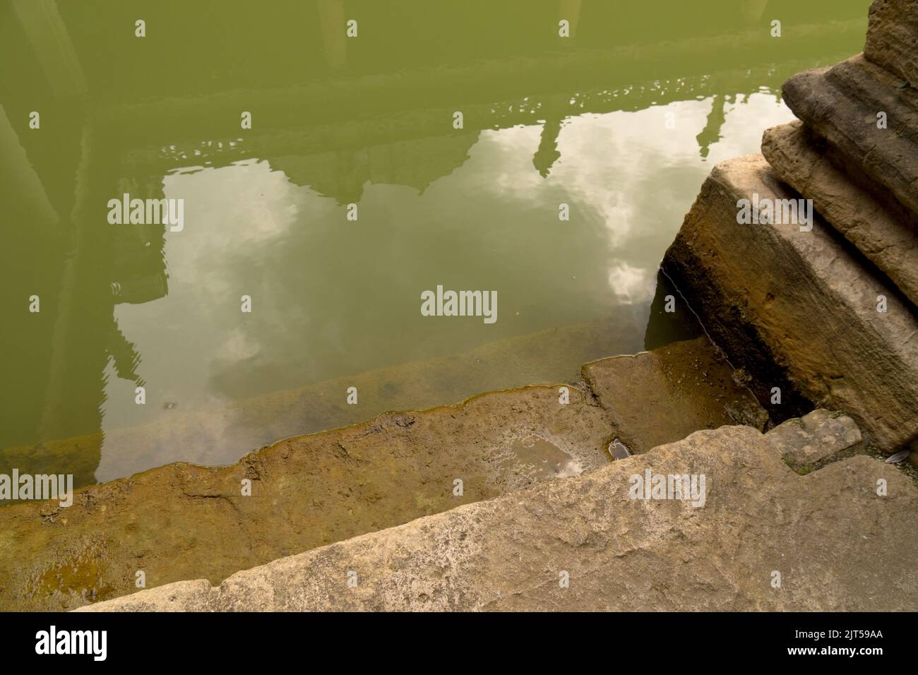 Detail ancient Roman bath with green water reflections stone walls ...
