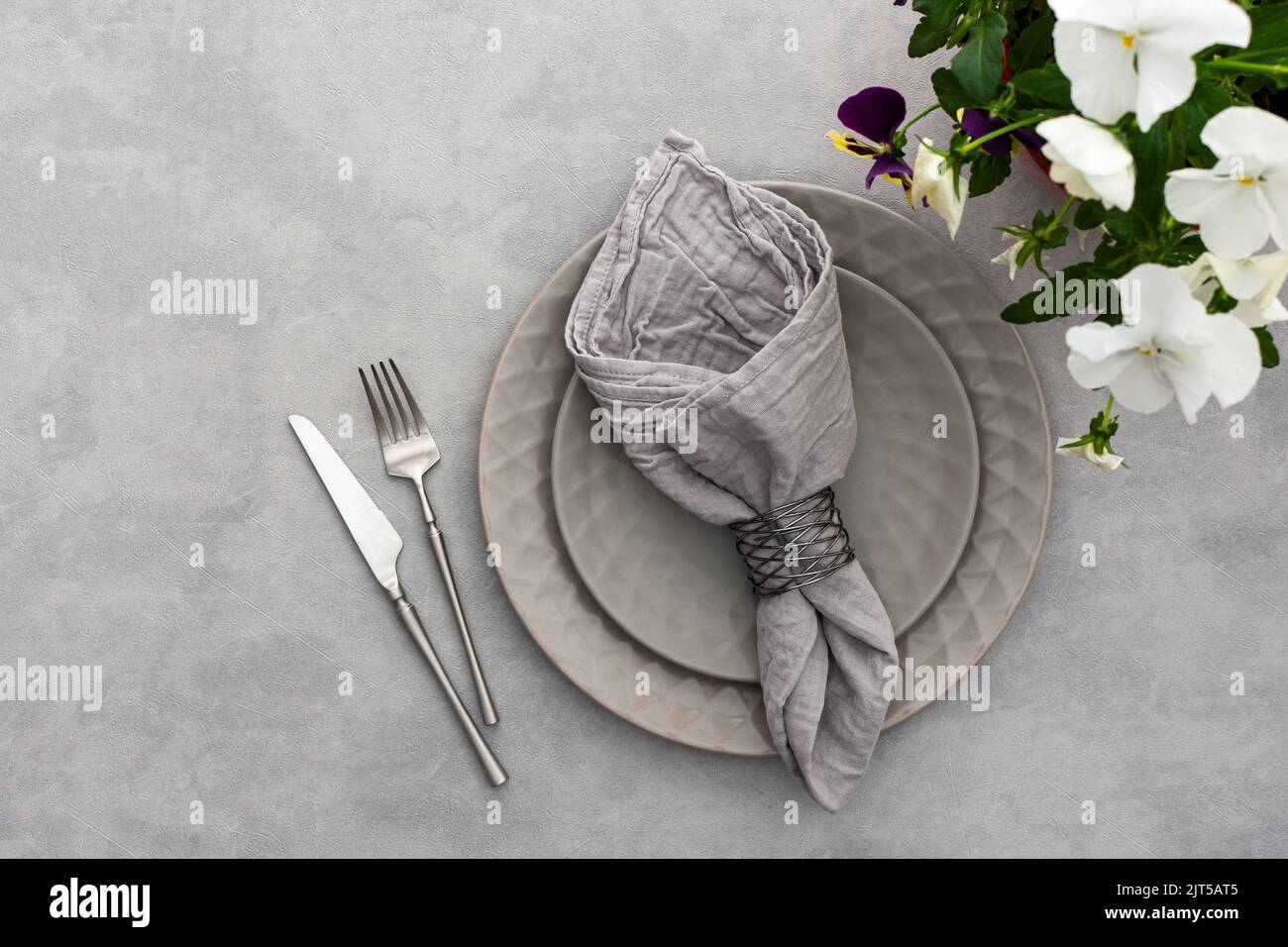 Table setting, empty plate with napkin and cutlery on the on the gray ...