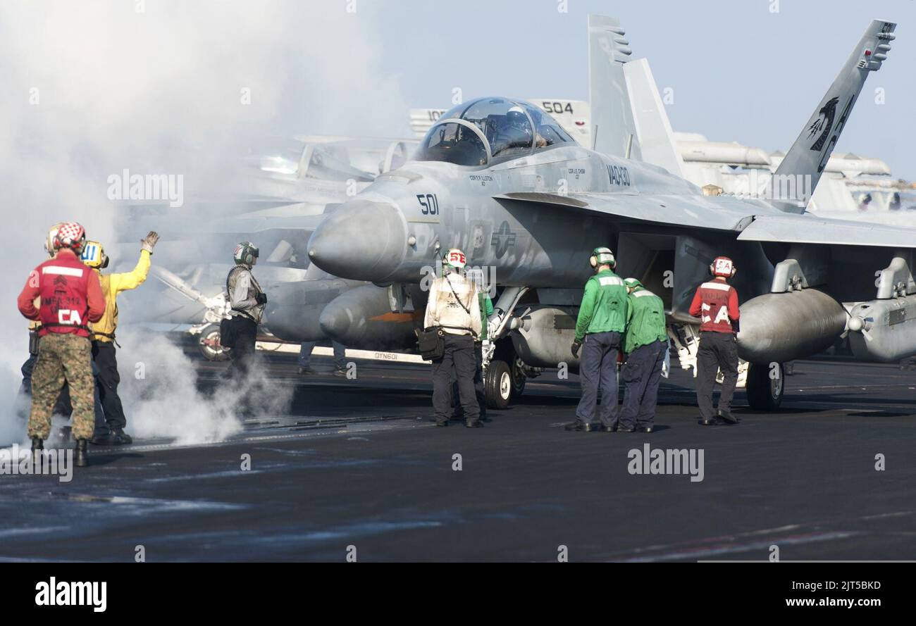 U.S. Sailors and Marines guide an EA-18G Growler aircraft assigned to ...
