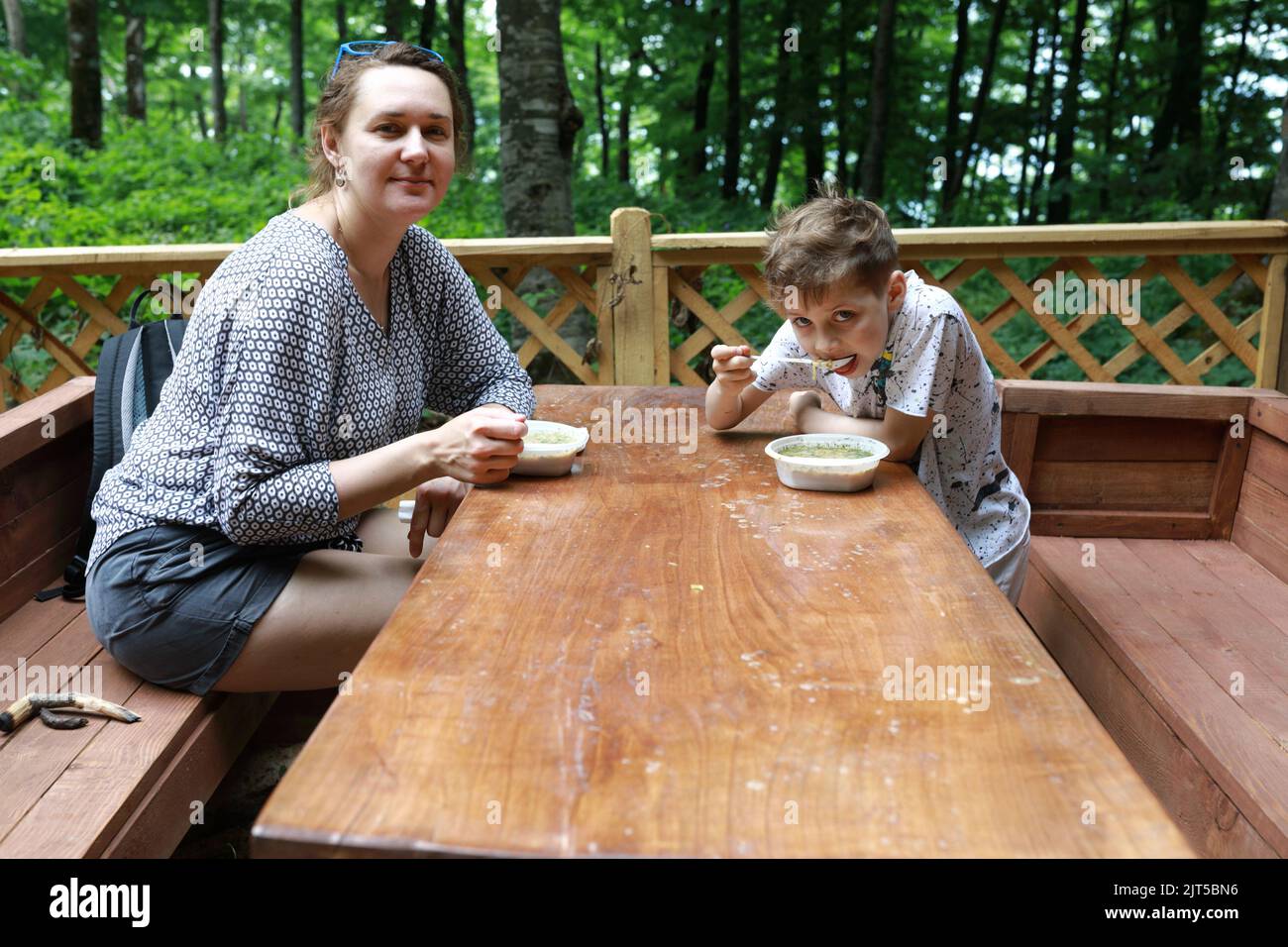 Mother and her son eating russian okroshka soup on terrace of ...