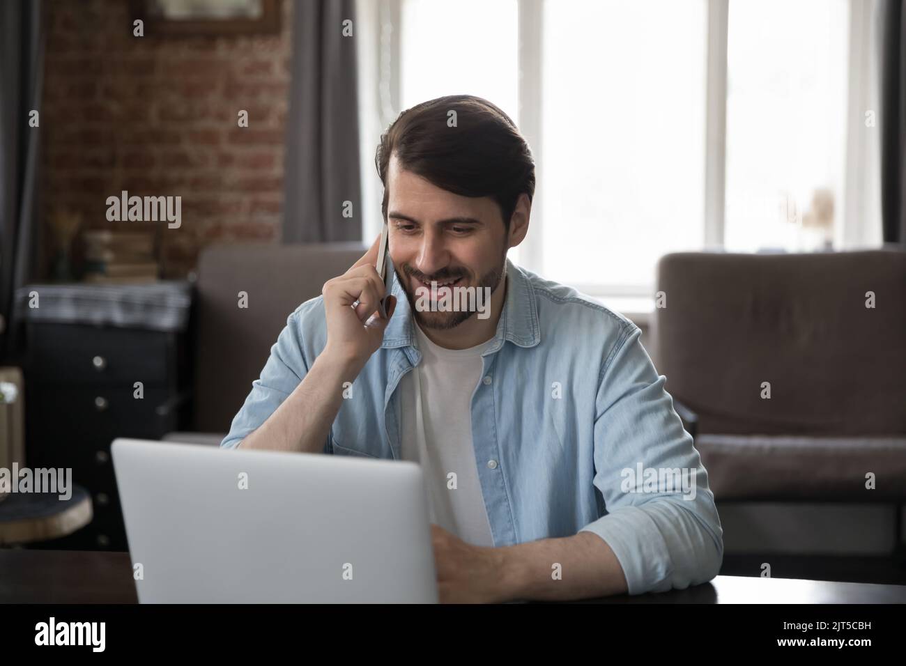 Happy engaged millennial freelance employee man answering cellphone ...